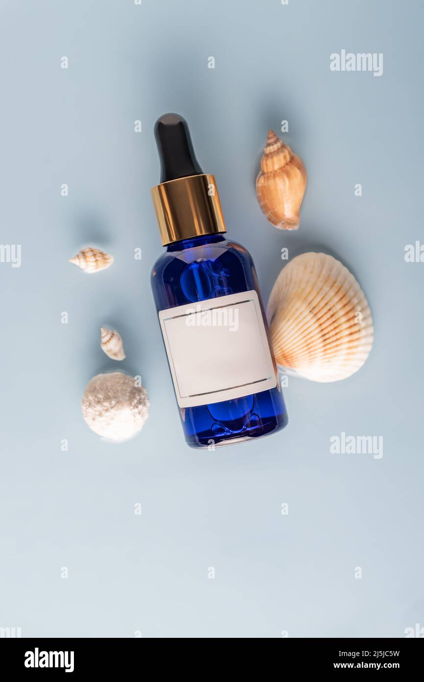 moisturizing face serum on a blue sea background with seashells.The ...
