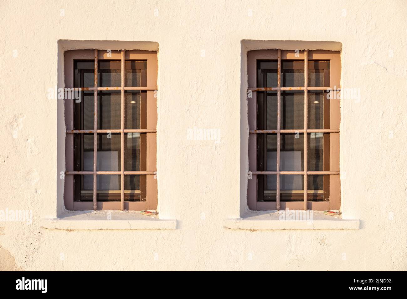 Two old windows with banister metal rusty railing on white wall ...