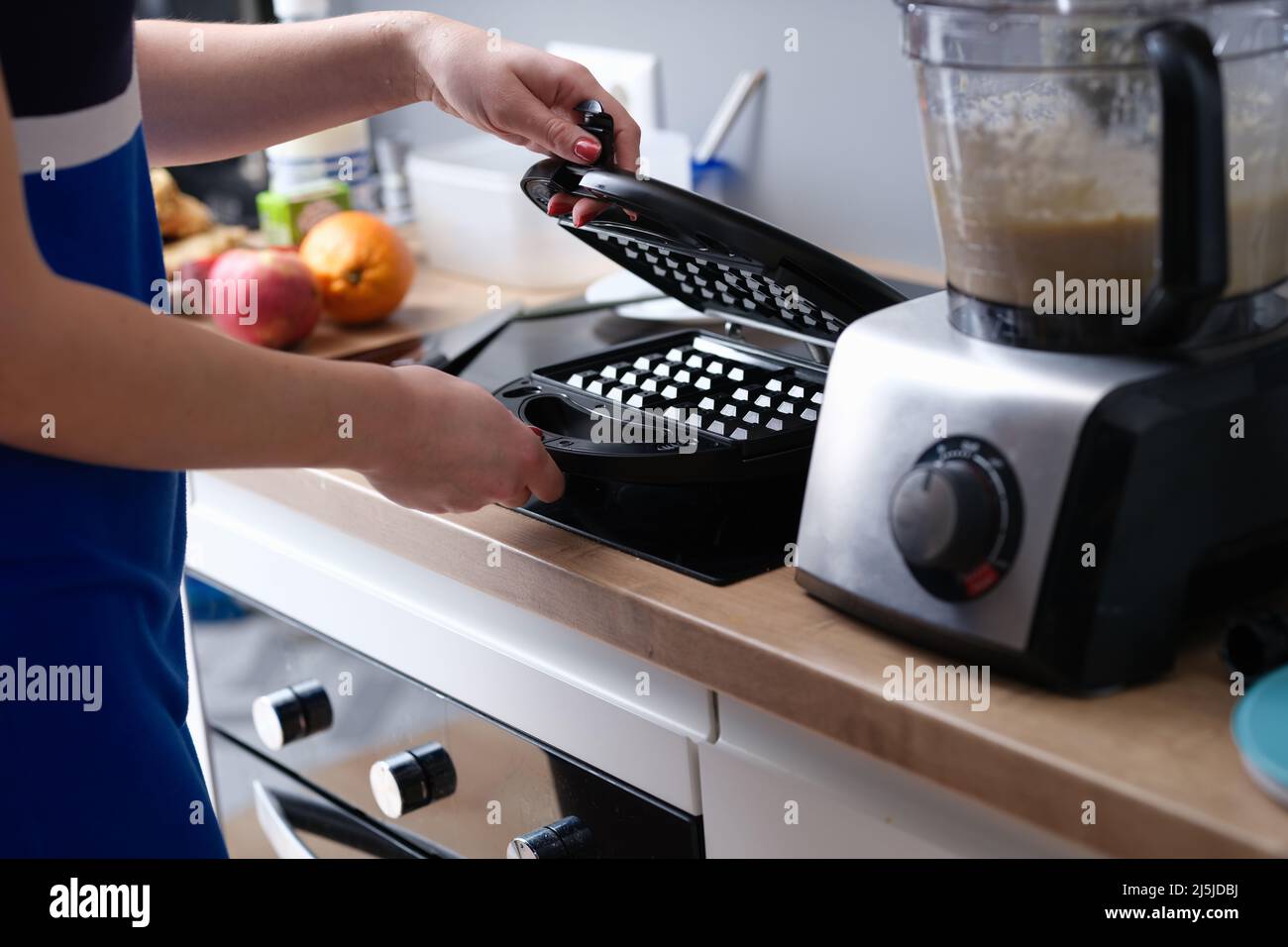 Woman opens electric waffle maker for Viennese and Belgian waffles ...