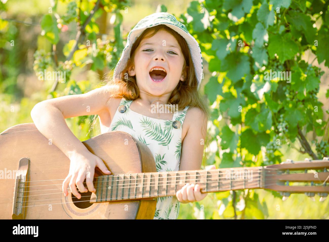 Excited child musician playing the guitar like a rockstar. Smiling ...