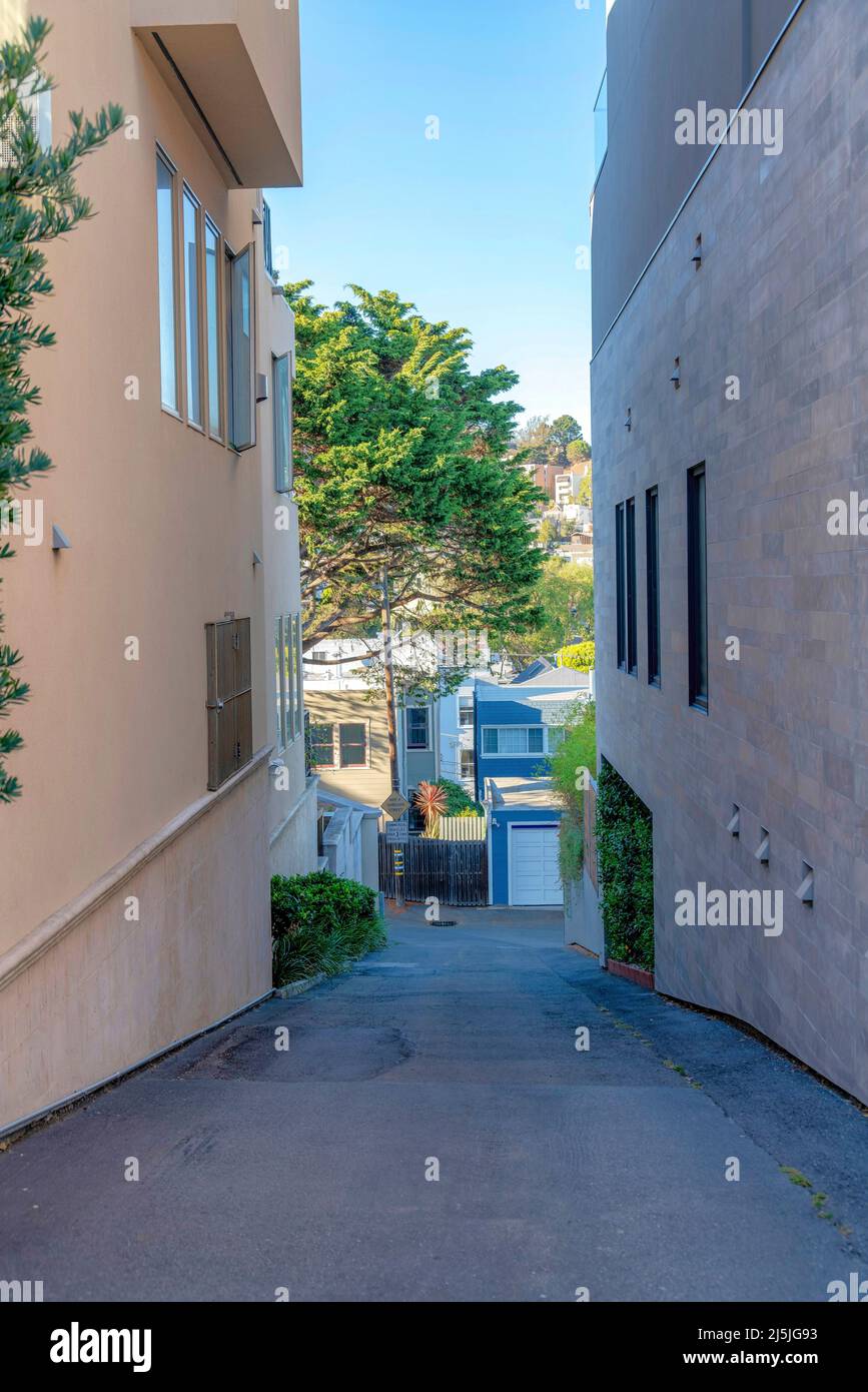 Downhill concrete pavement in the middle of two tall buildings at San ...