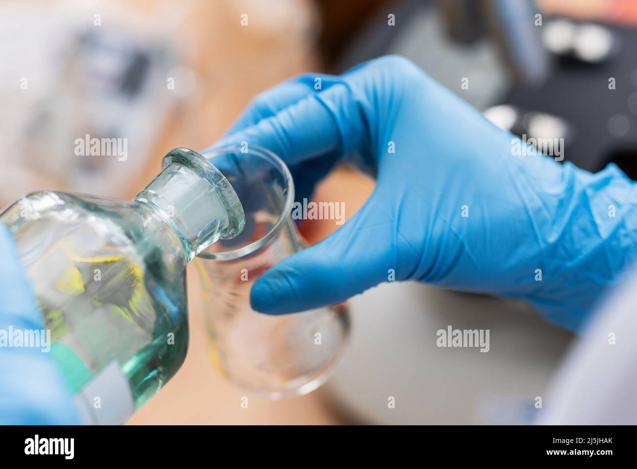 Scientist pouring substance from one flask to another in a laboratory during research work Stock ...