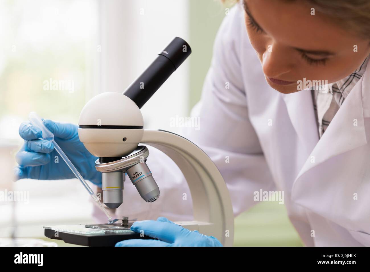 Woman scientist is using microscope in a laboratory during research ...