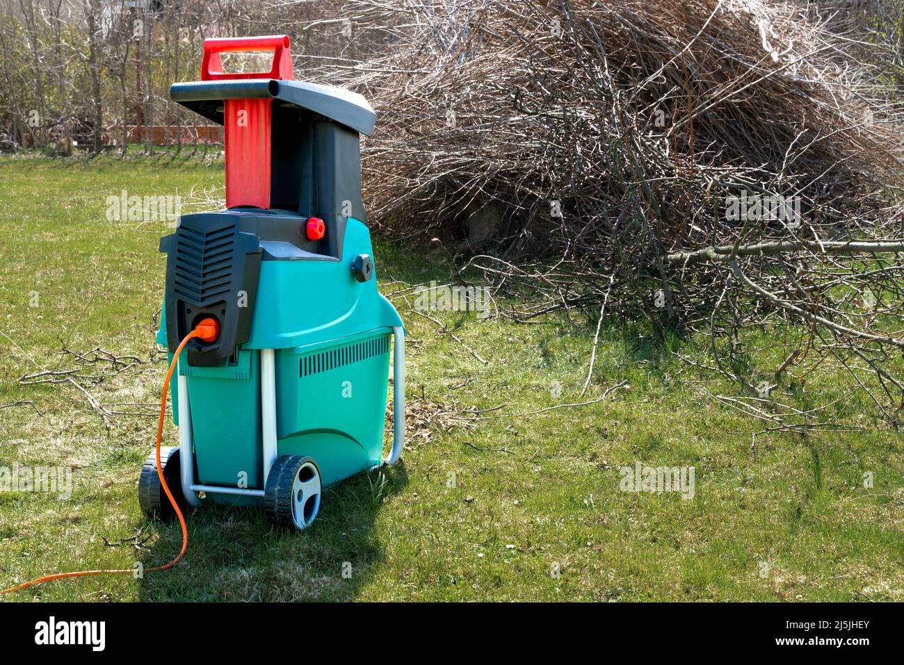 Electric garden shredder with weathered lawn and pile of cut tree ...