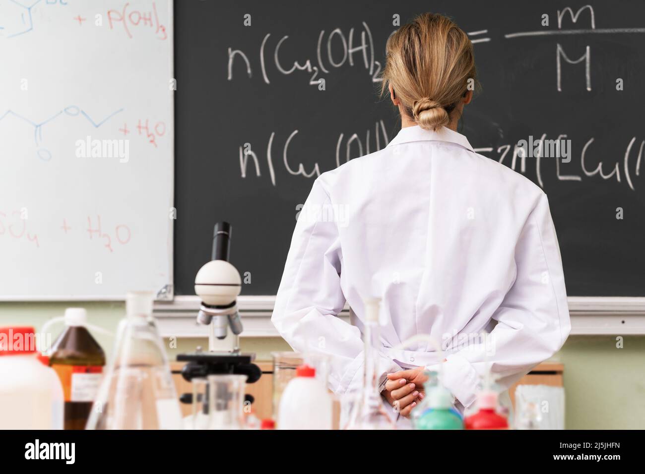 Scientist looking at chemical equation on a chalkboard during a ...