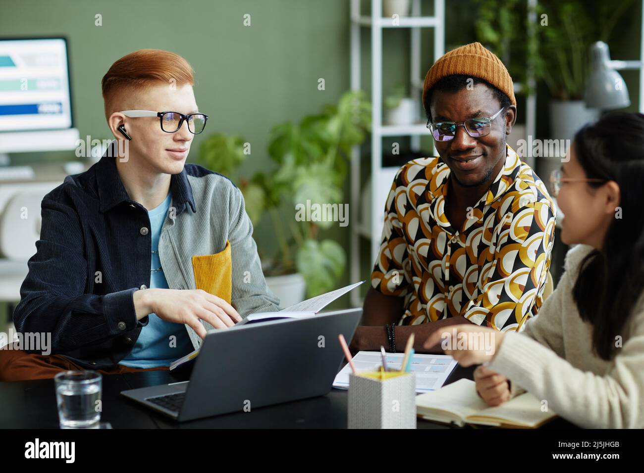 Portrait of young creative team collaborating in business meeting while ...