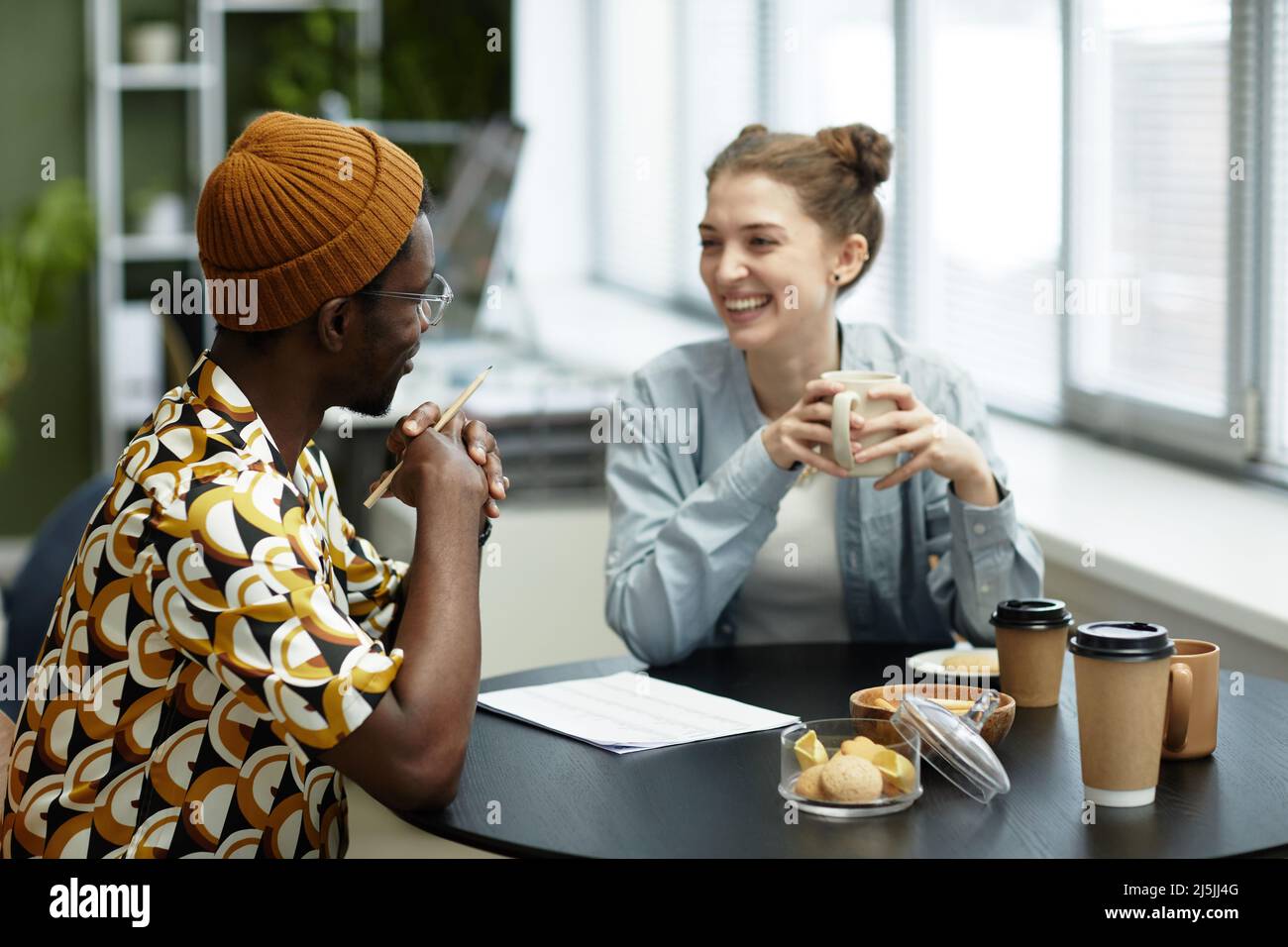 Portrait of two creative young people laughing together while enjoying ...