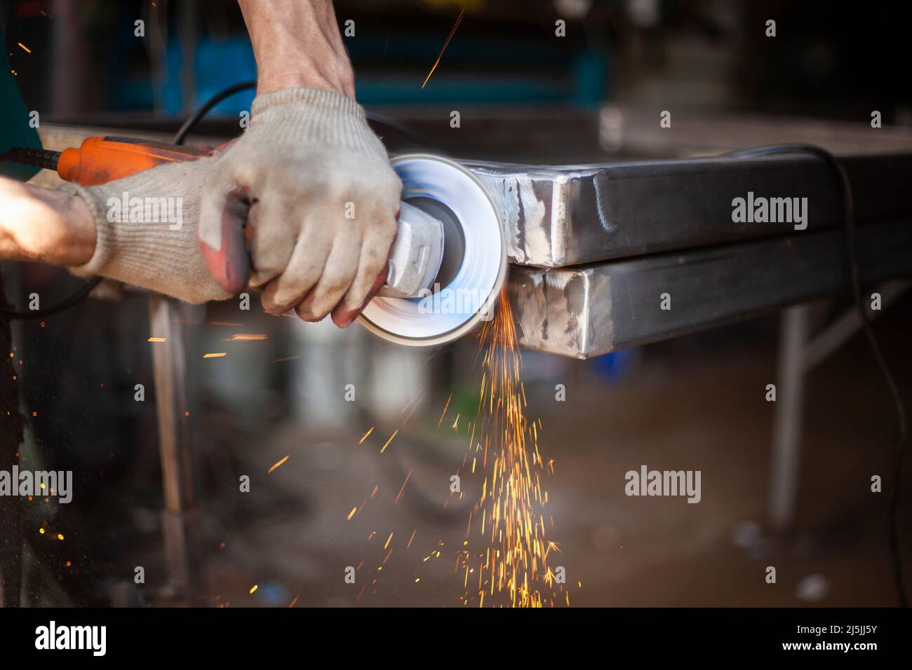 Grinding of metal. Sparks from power tools. The man works in the garage ...