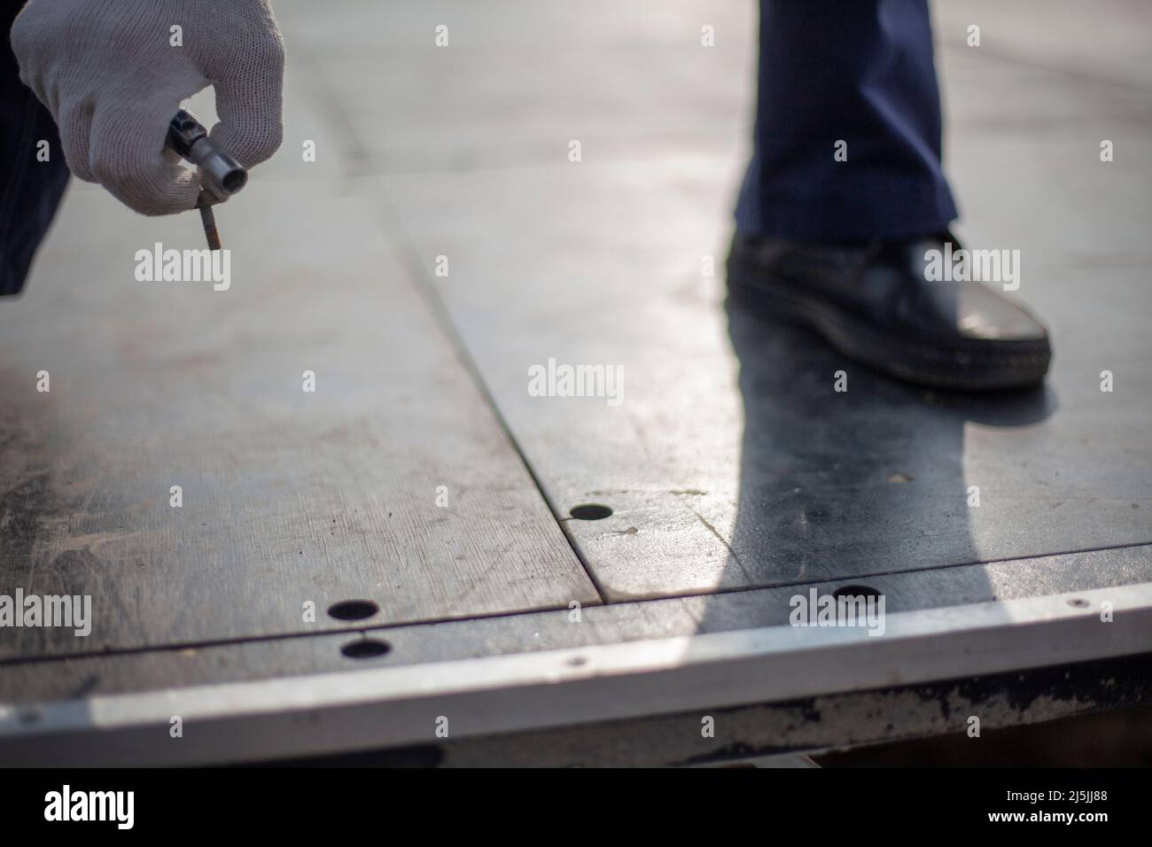 Worker holds bolt. Man tightens screw. Guy assembles structure. Fitting ...