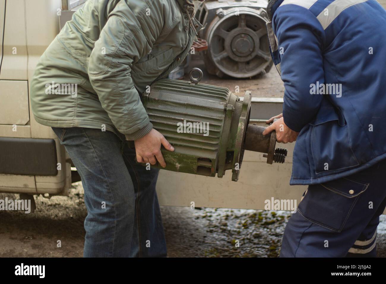 Men lift the engine. The engine from the elevator is in the hands of ...