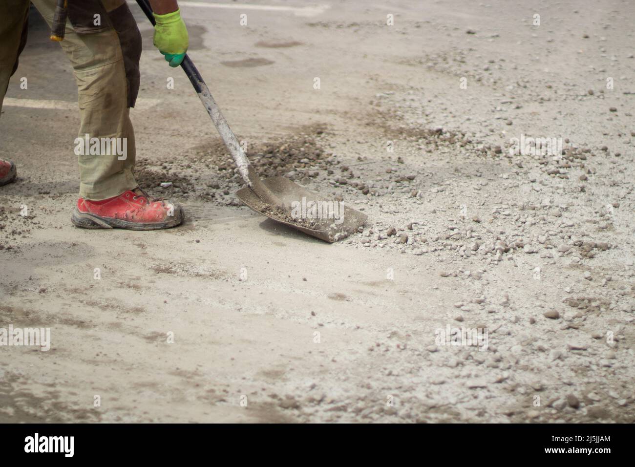 Work with a shovel at a construction site. A worker throws cement and ...