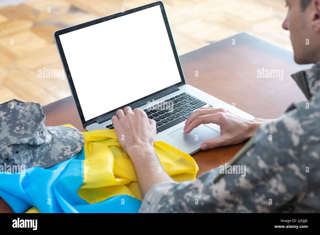 military man gesturing in office near laptop with blank screen, flag of ...