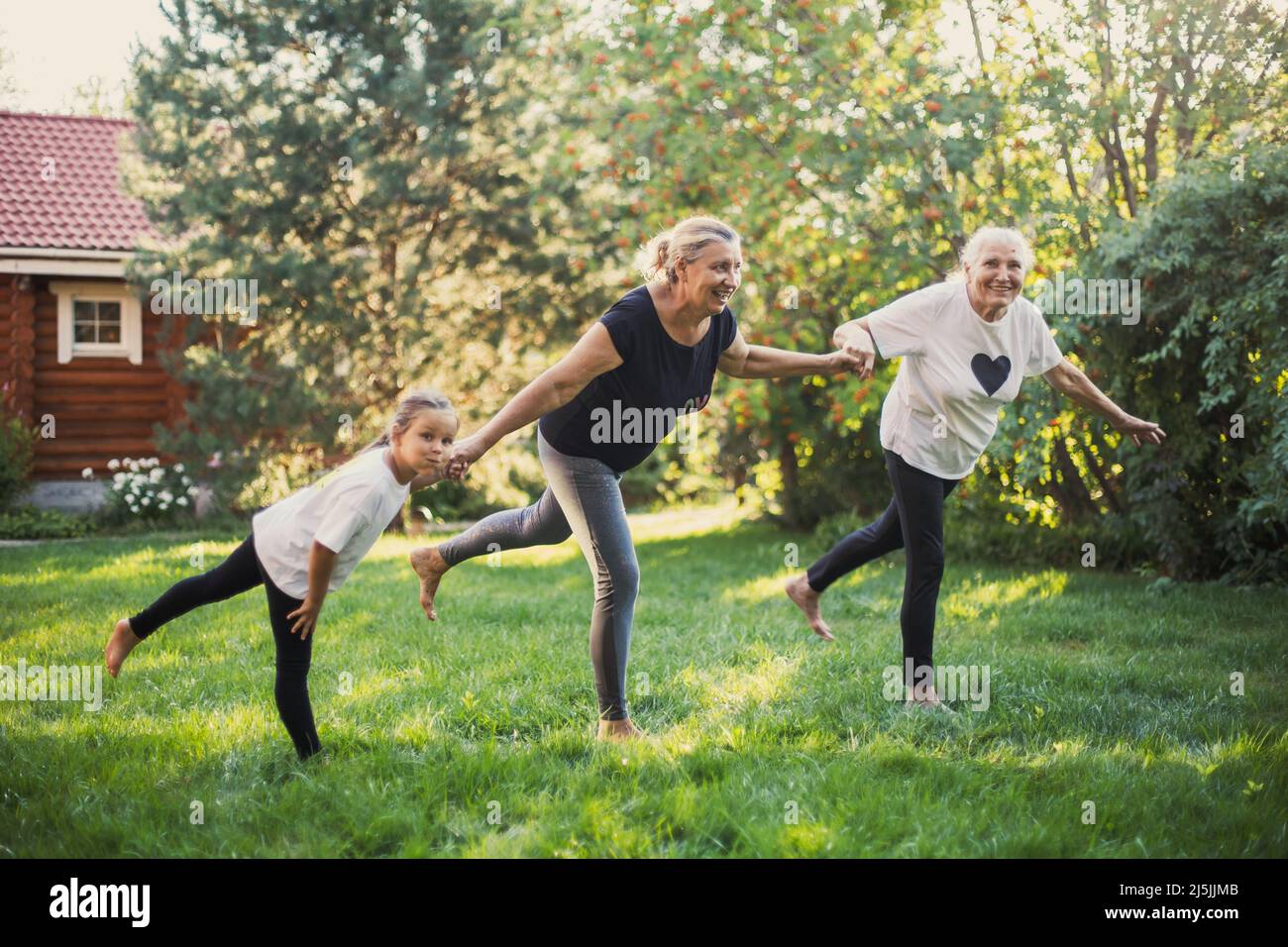 Three generations of family females smiling balancing on one leg ...