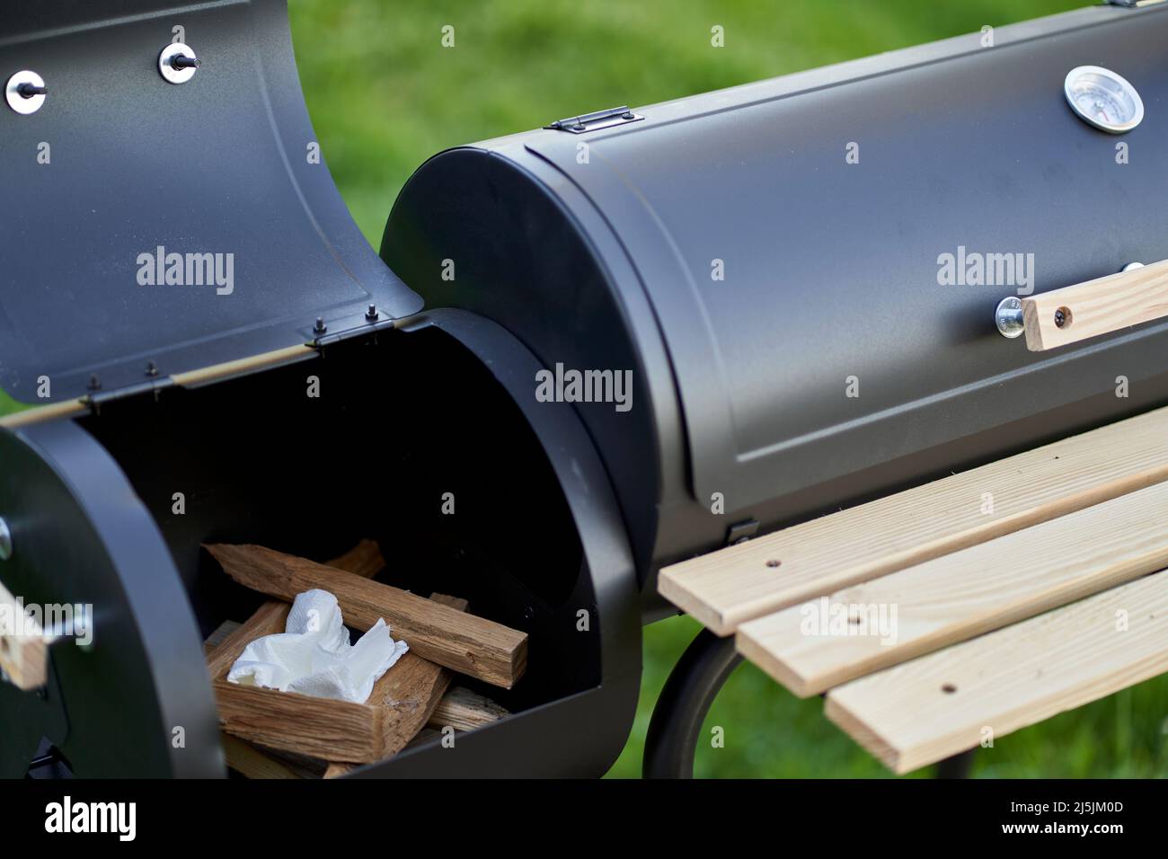 New smoker barbecue grill. Stack wood and light it properly. Closeup ...