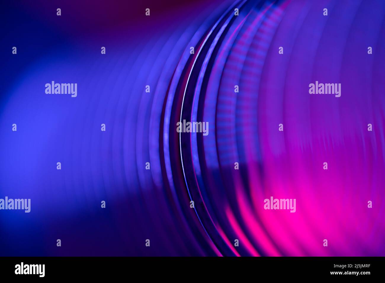 Closeup of coiled metal spring rings in a compressed state in red neon ...