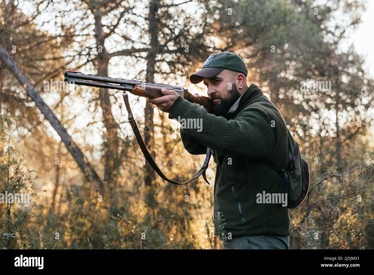 Bearded man aiming rifle while hunting in forest Stock Photo - Alamy