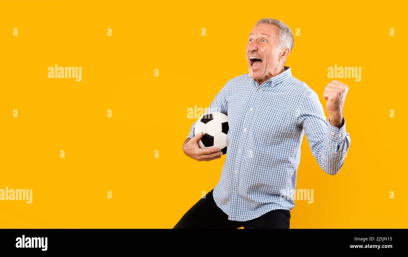 Mature man screaming holding soccer ball on yellow background Stock ...