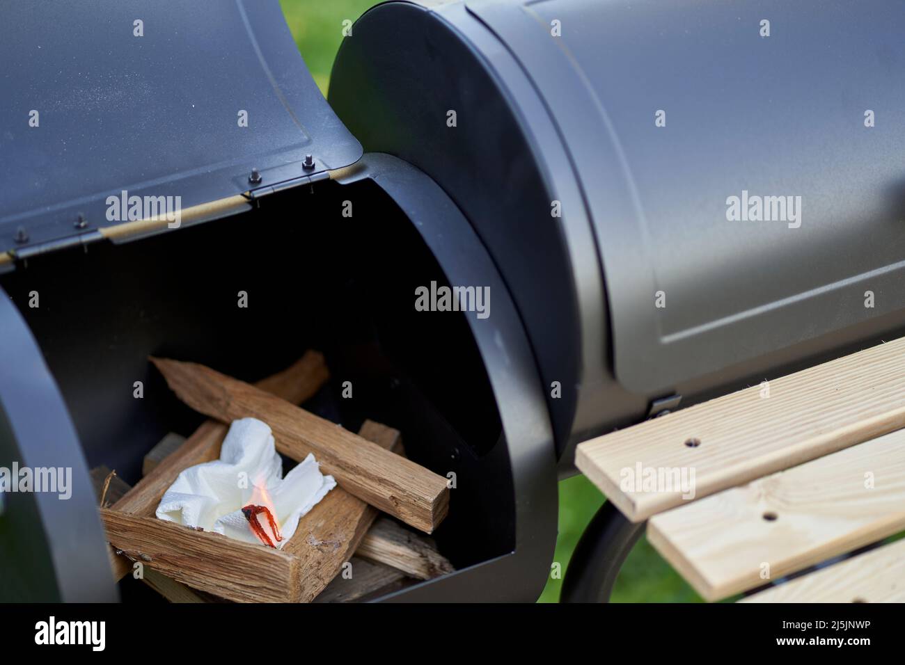 New smoker barbecue grill. Stack wood and light it properly. Closeup ...