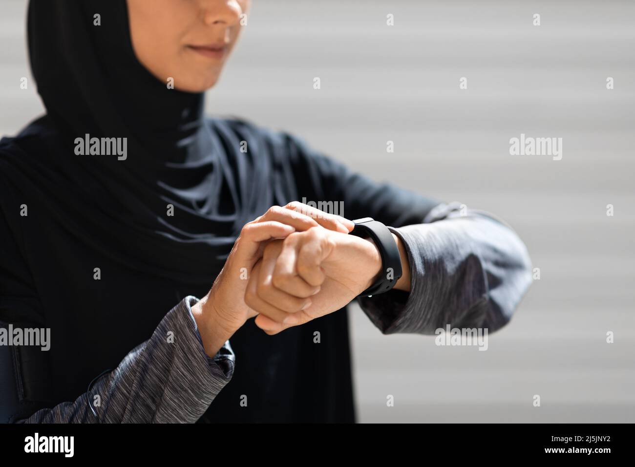 Confident young arab lady athlete in hijab checks pulse on fitness ...