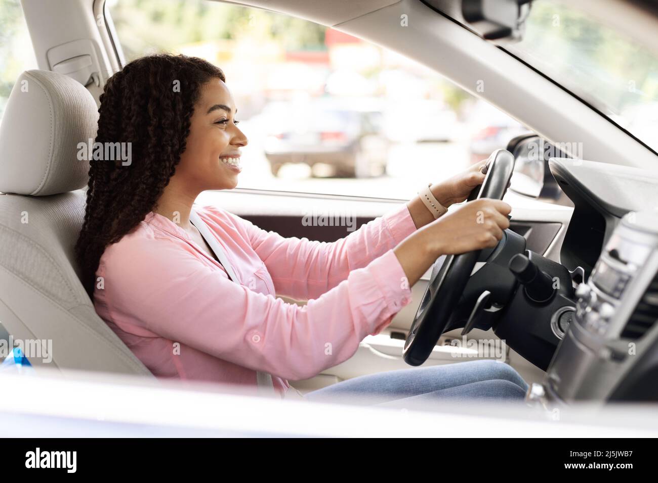 Smiling black woman driving new car in city Stock Photo - Alamy