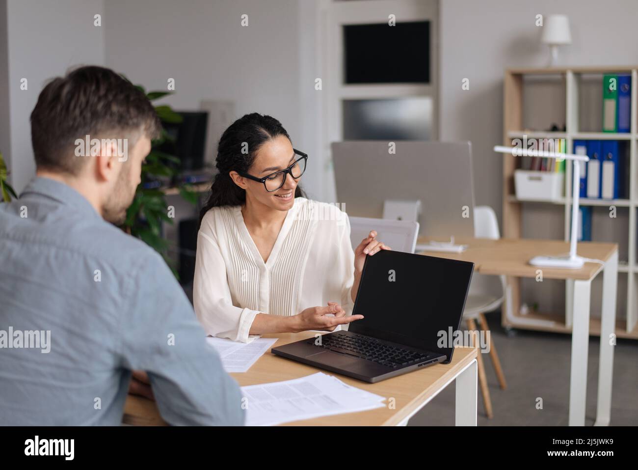 Positive male and female employees discussing business project, using ...