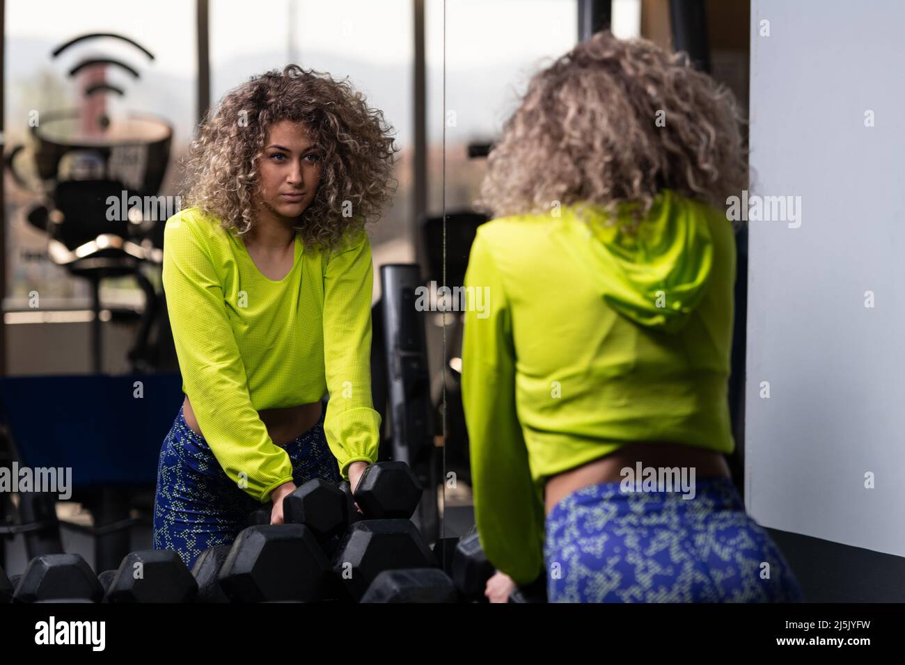 Attractive Young Woman Standing Strong In The Gym And Flexing Muscles ...