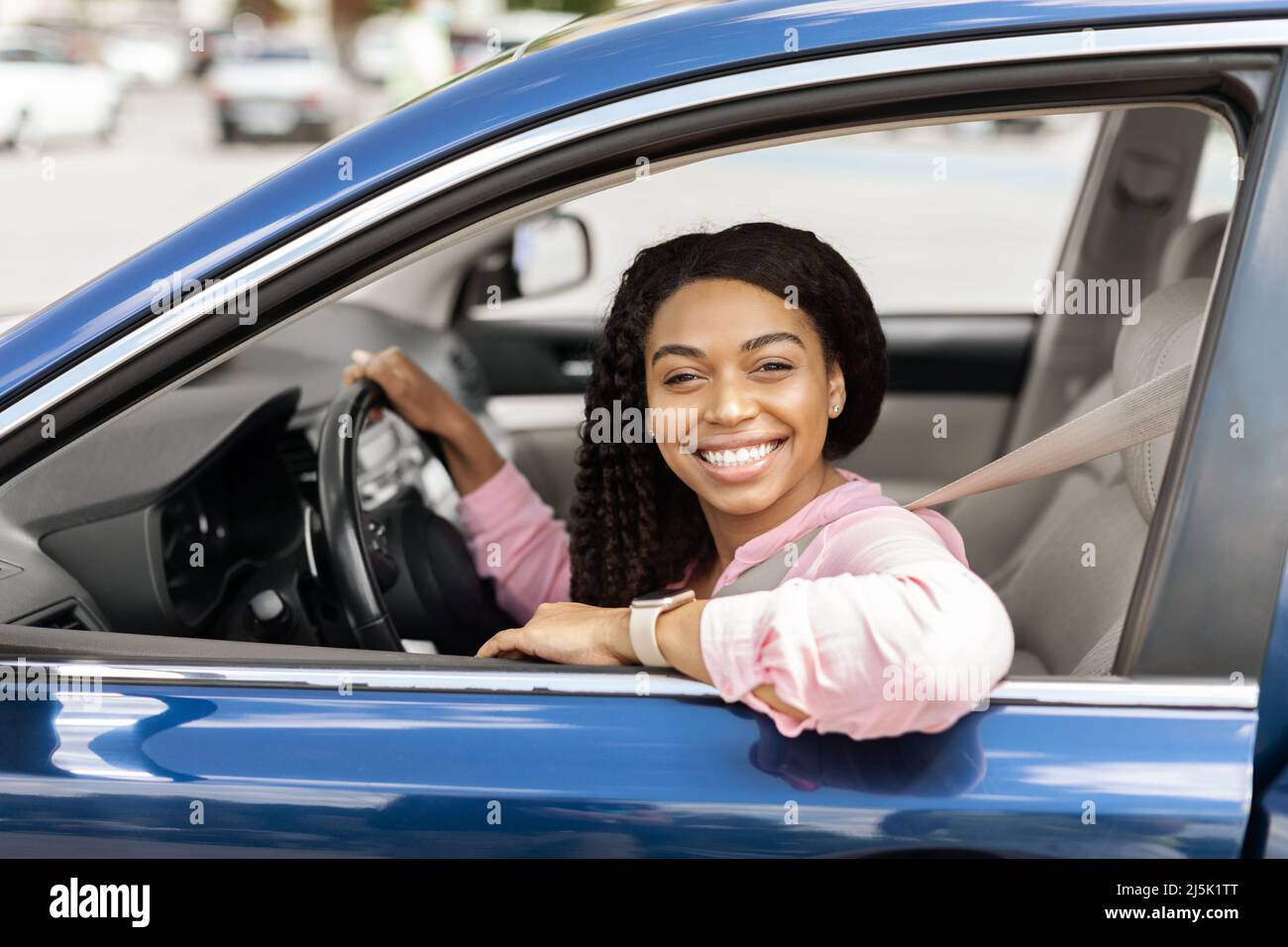 Smiling black woman driving new car in the city Stock Photo - Alamy