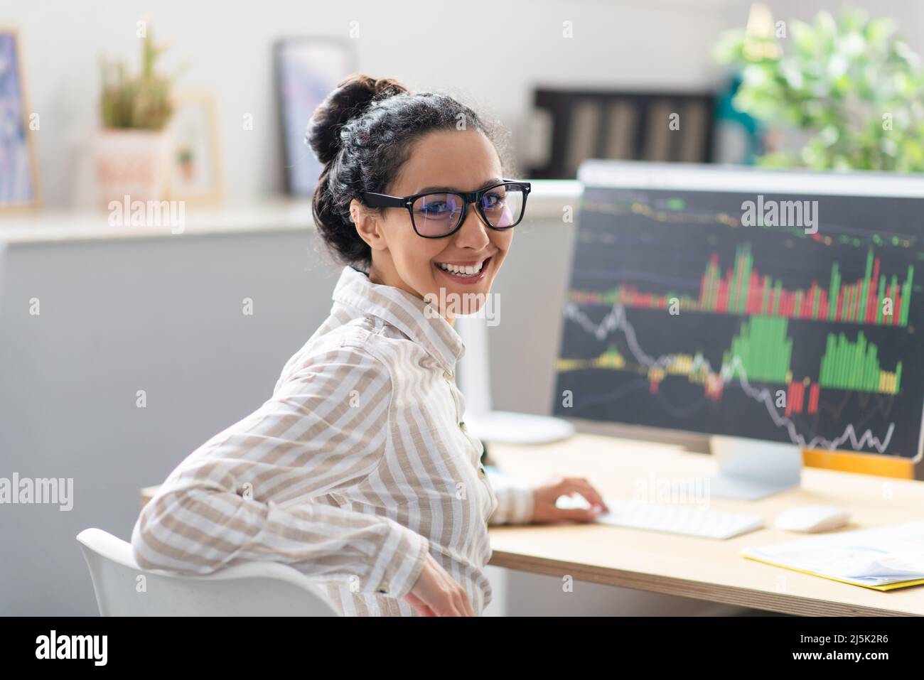Happy businesswoman sitting at workplace in office and smiling at ...