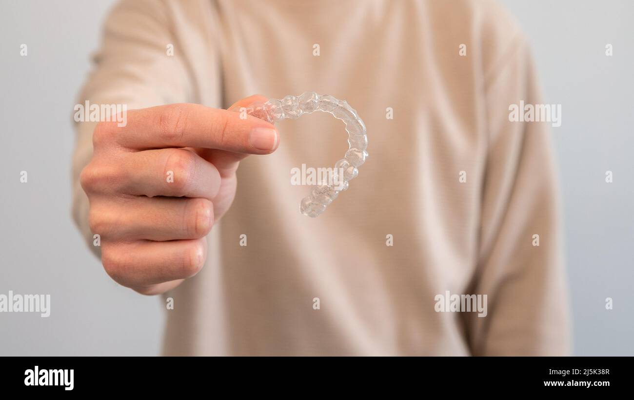 Adult man holds invisalign transparent braces for dental correction ...