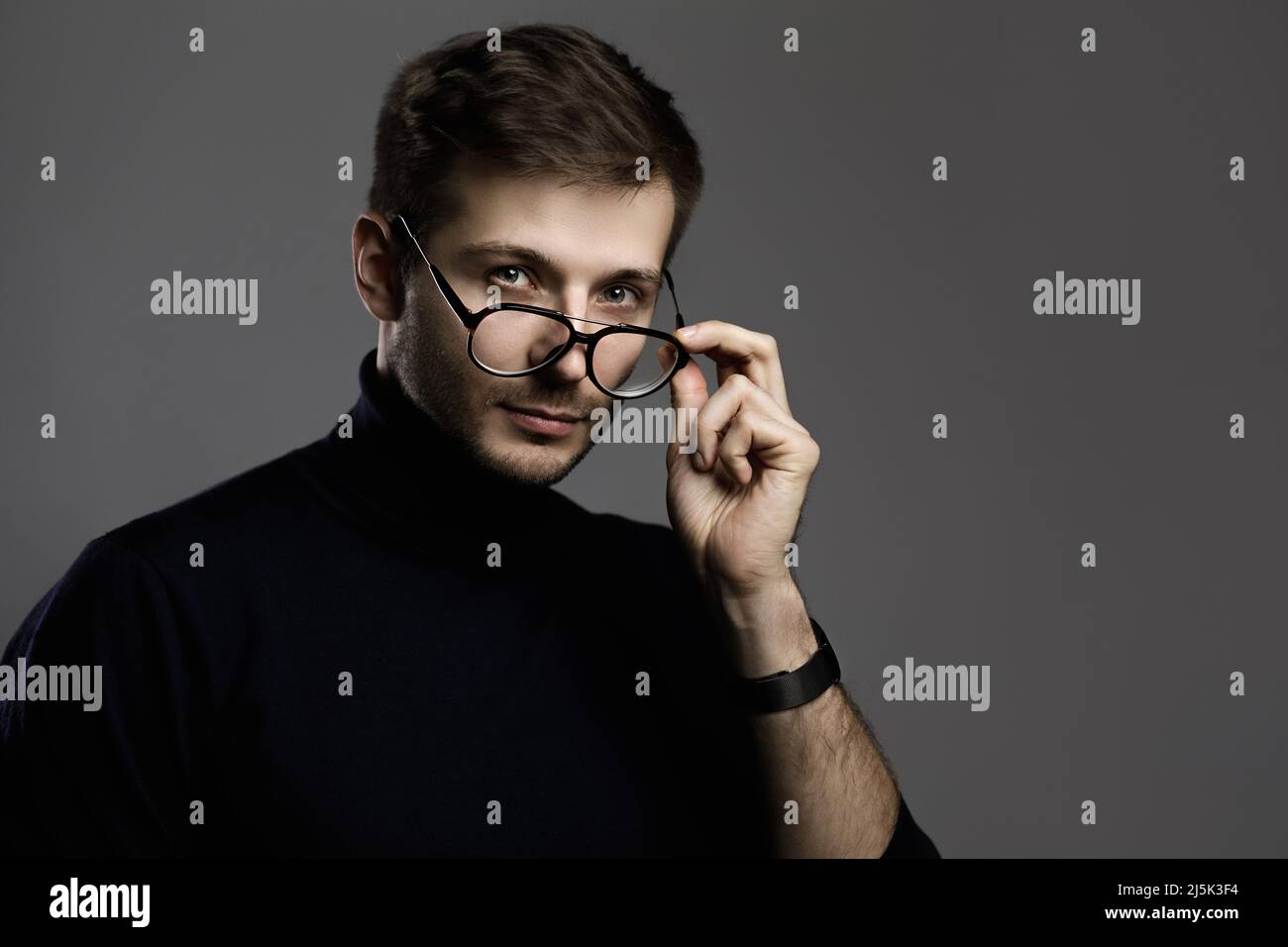 Young intelligent man wearing turtleneck and eyeglasses on gray ...