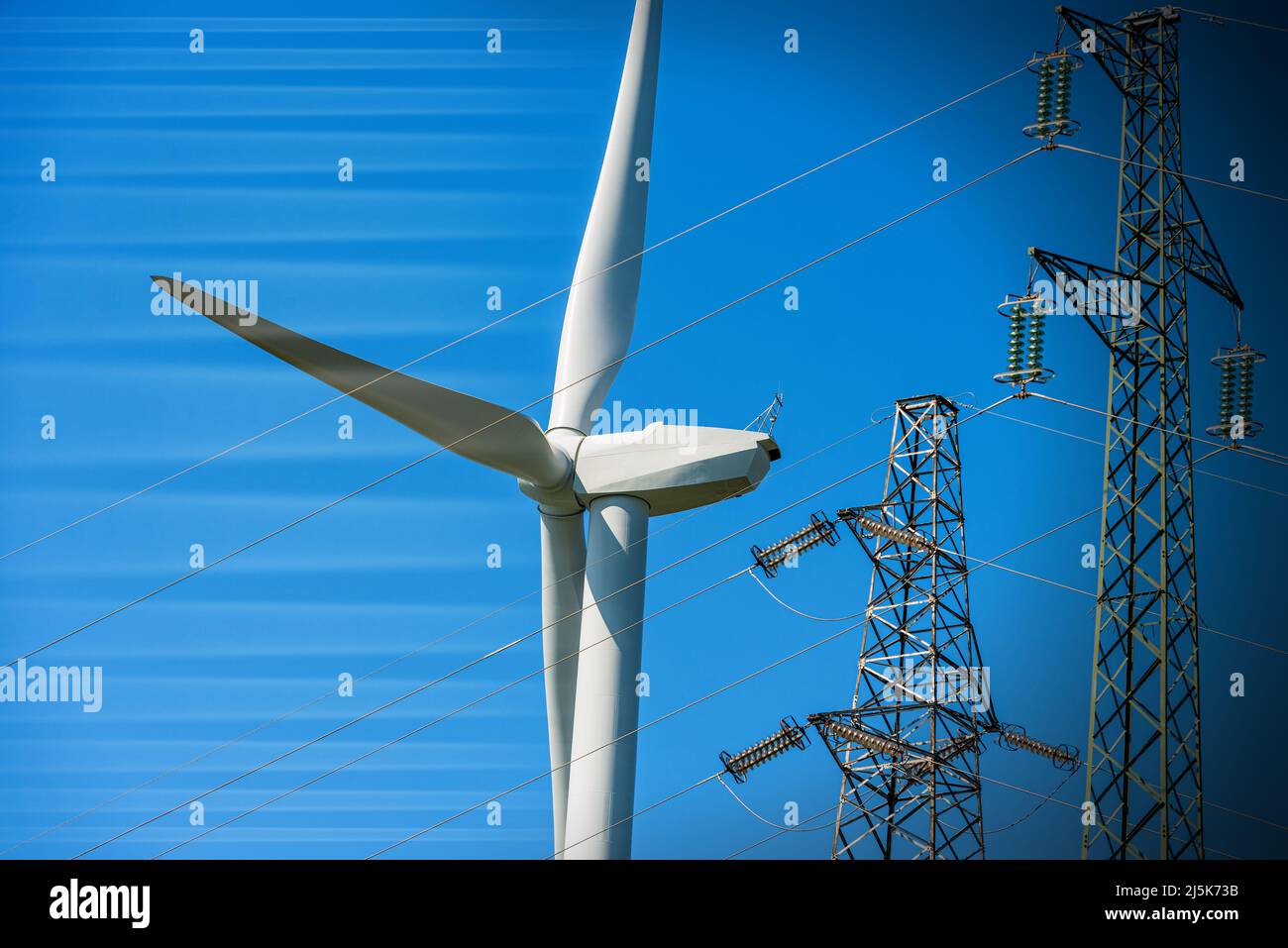 Close-up of a white wind turbine and high voltage towers (power line ...