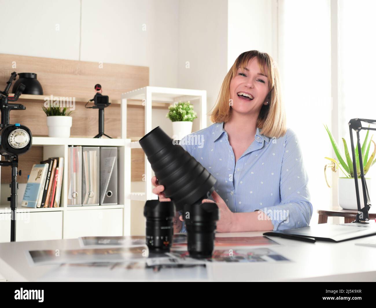 Female photographer working at office studio and holding a snoot ...