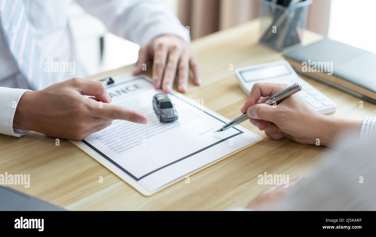 Insurance concept the male dealer suggesting his customer to sign the ...