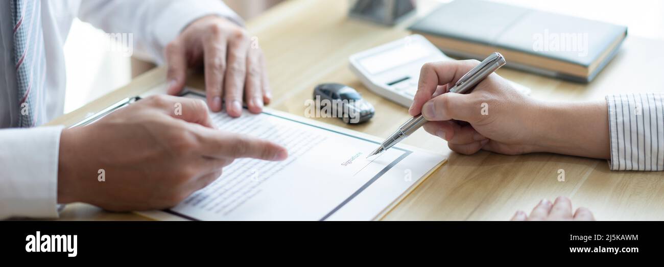 Insurance concept the male dealer suggesting his customer to sign the ...