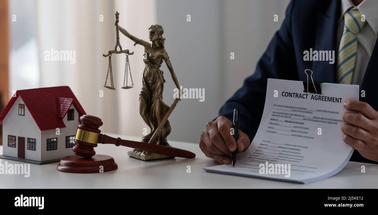 Lawyer in the office with brass scale and pointing in contract on ...