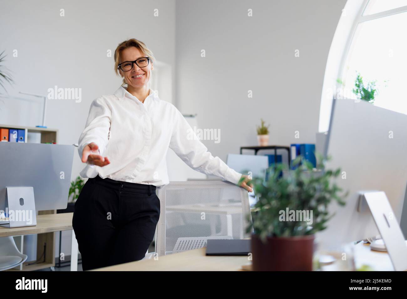 Friendly female office worker in glasses and formal wear showing ...