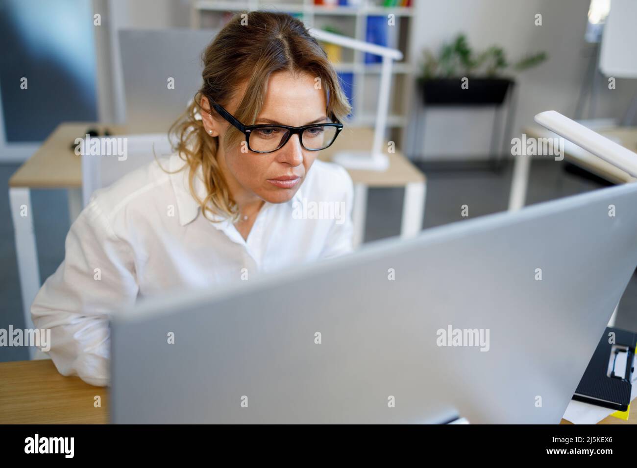 Shot with concentrated mature business woman looking at computer screen ...