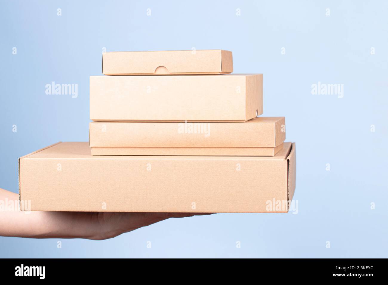 Stack of cardboard boxes in female hands. Blank brown parcel boxes on ...