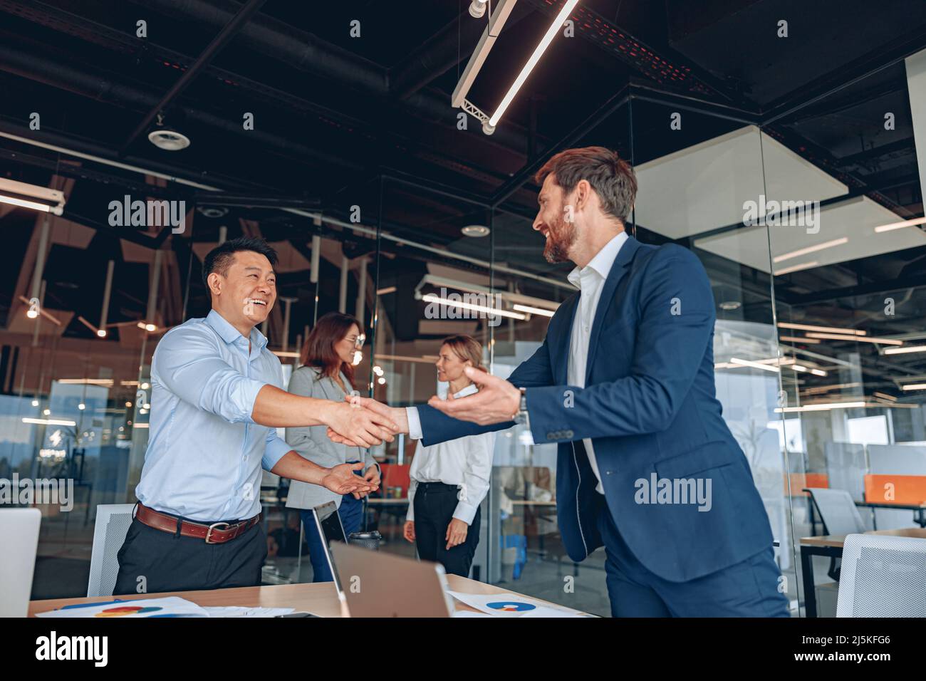 colleagues are shaking their hands in modern office during teamwork ...