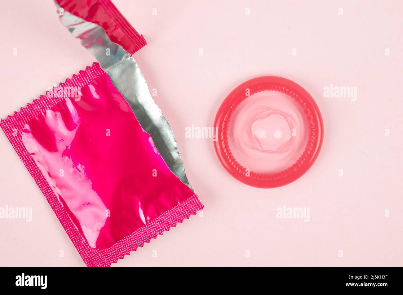 The Pink opened condom and condom in pack on a pink background Stock ...