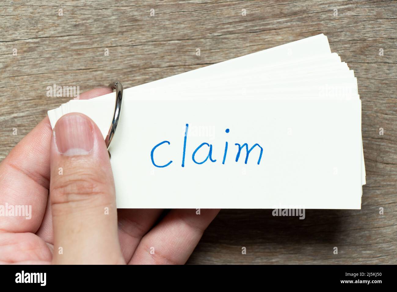 Man hold the flash card with handwriting word claim on wood background ...