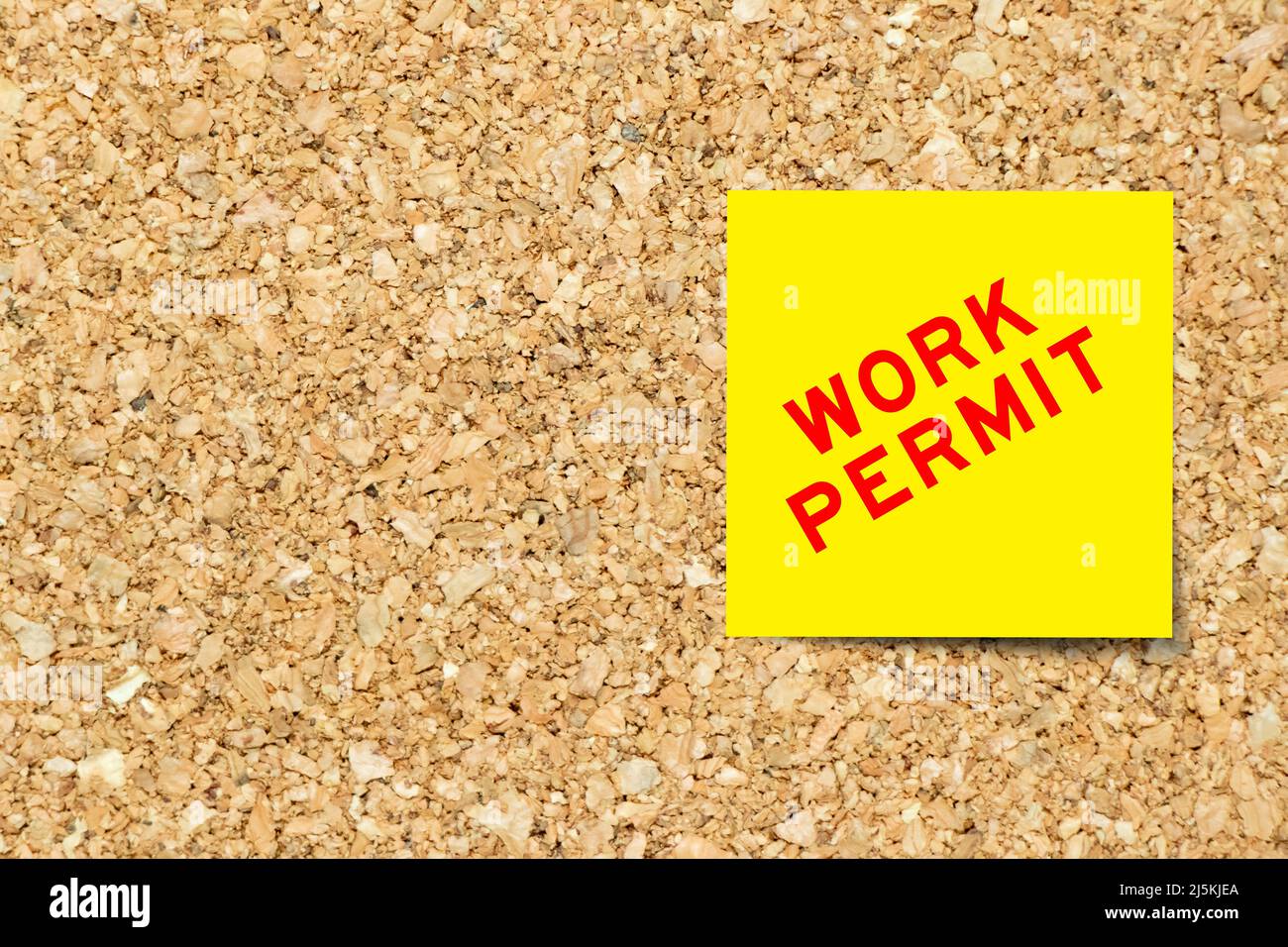Yellow note paper with word work permit on cork board background with ...