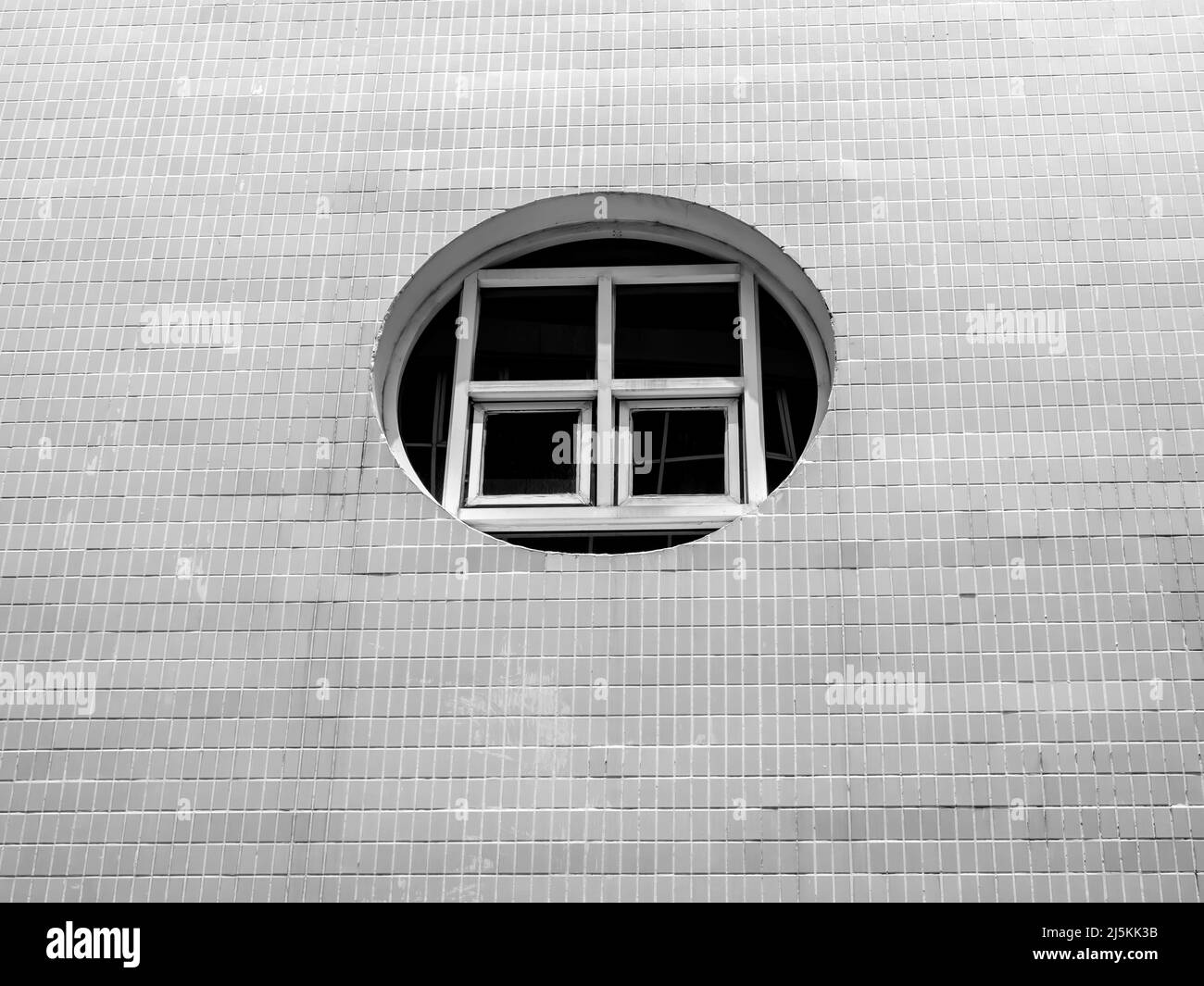 Old round window on white clean outdoor building with mosaic wall, view ...