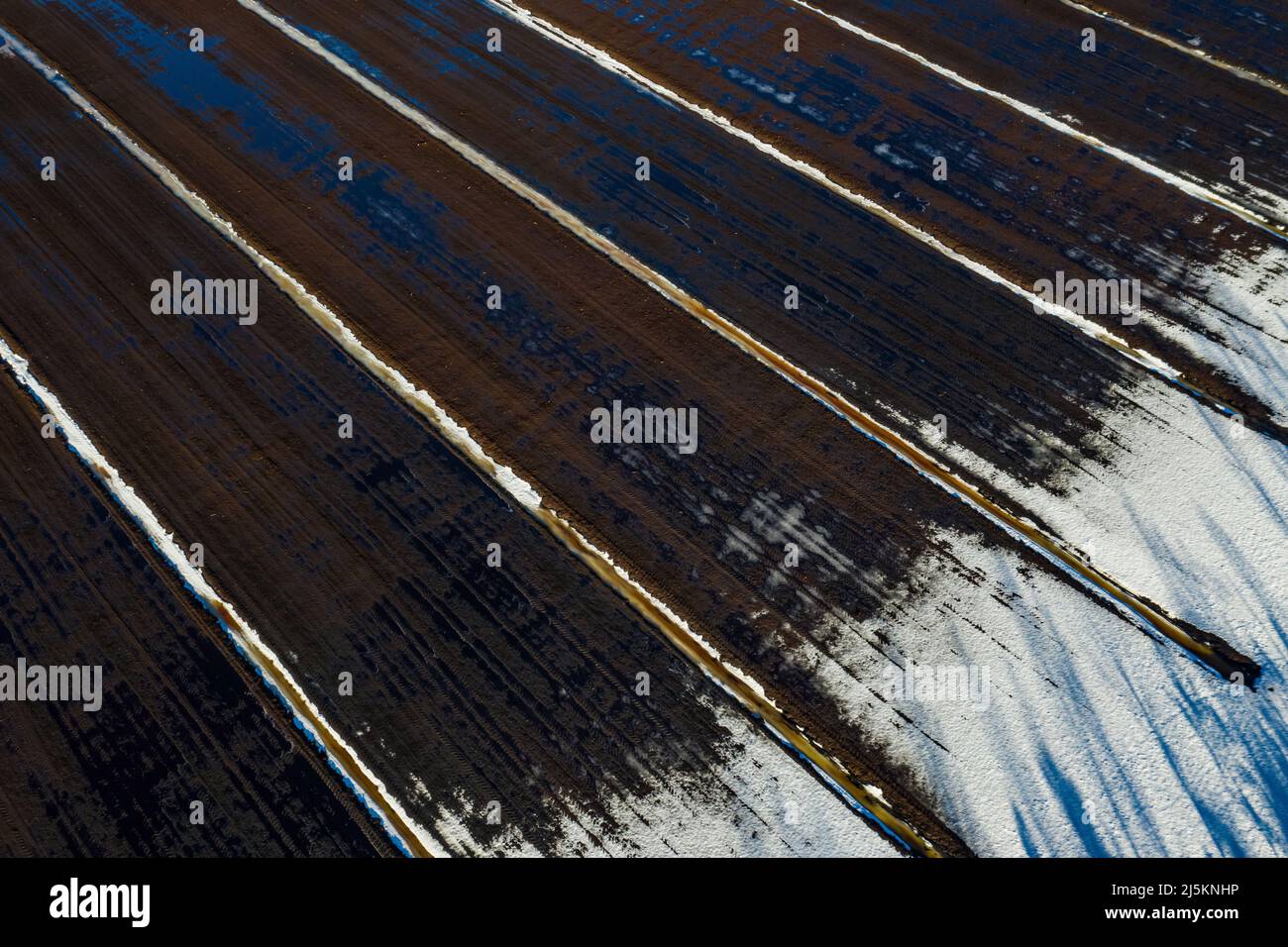 Top drone view of early spring dirty field with puddles and melting ice ...