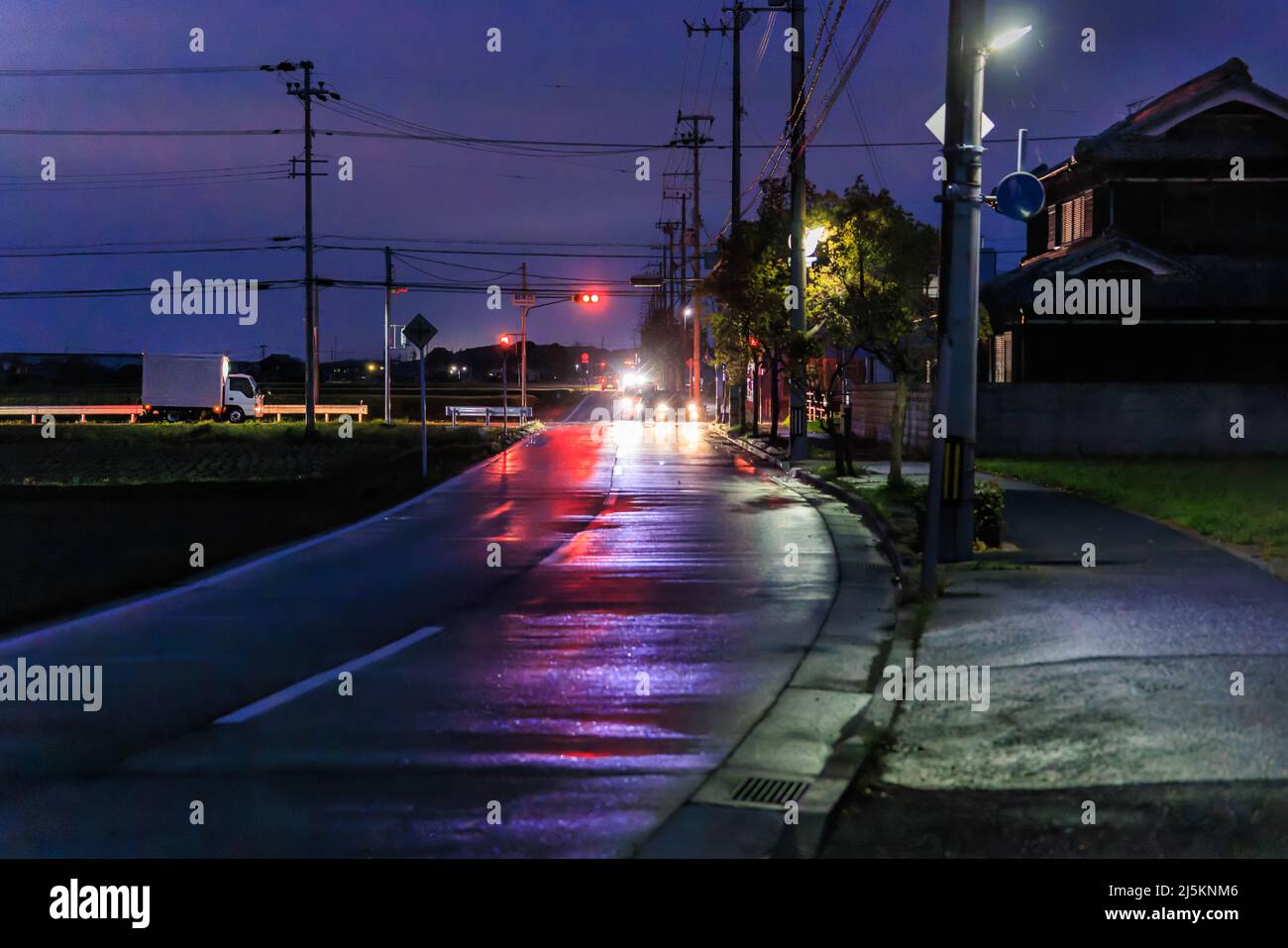 Street and traffic lights reflect off wet road after rain storm at ...
