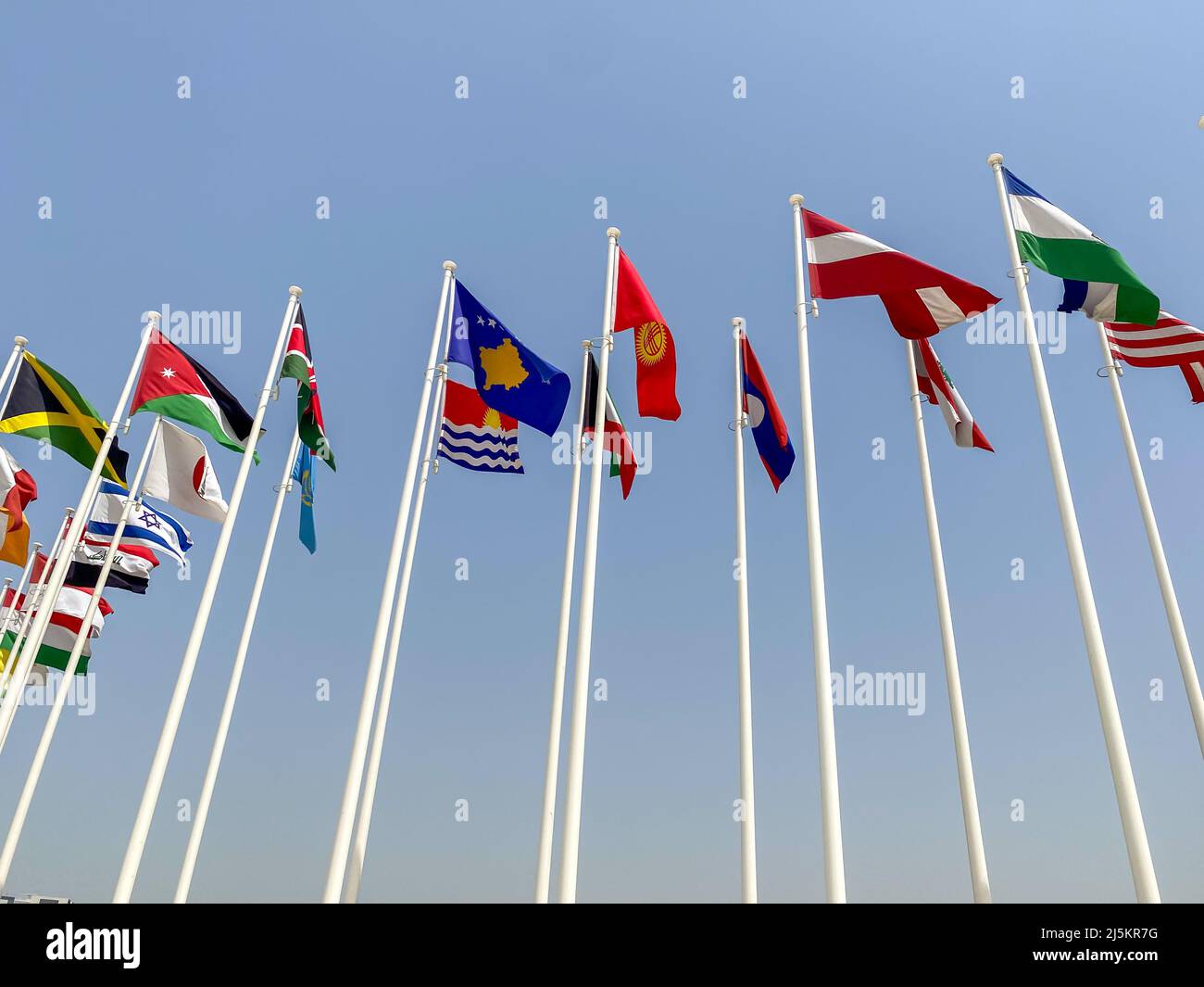 Looking up to Many world flags flying in a row outside of expo center ...