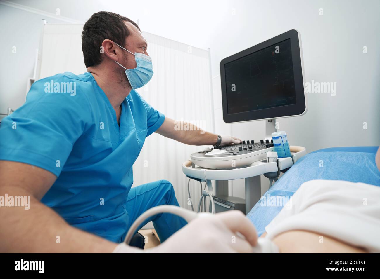 Caucasian doctor performing an ultrasound of the internal organs on ...