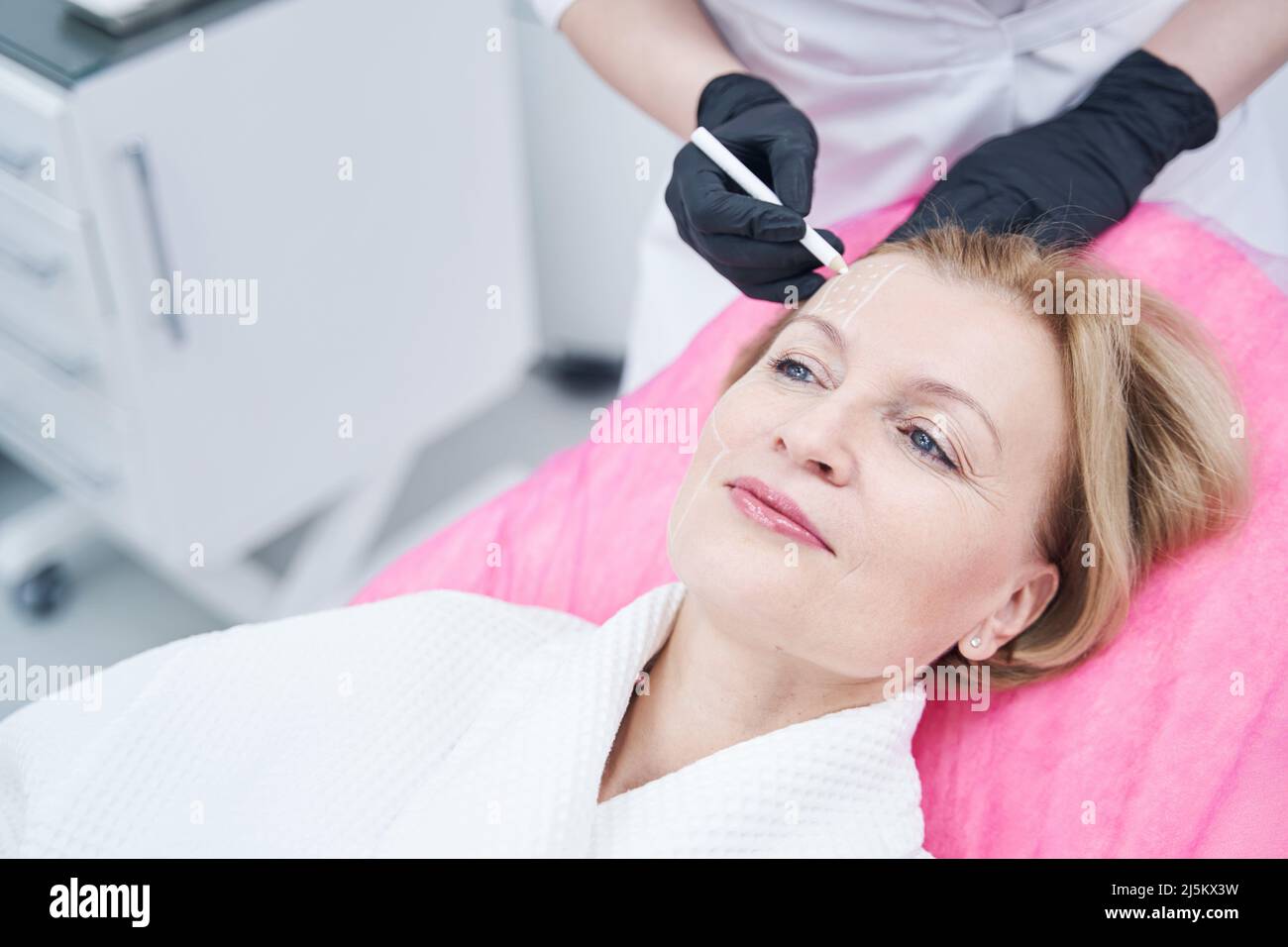 Beautician drawing line on woman face in beauty salon Stock Photo - Alamy