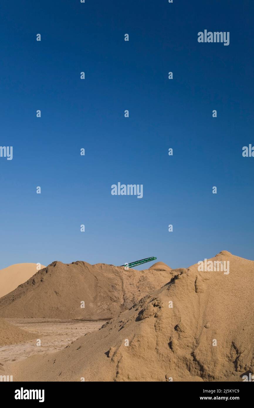 Mounds of fine sand and a stacking conveyor in a commercial sand pit ...