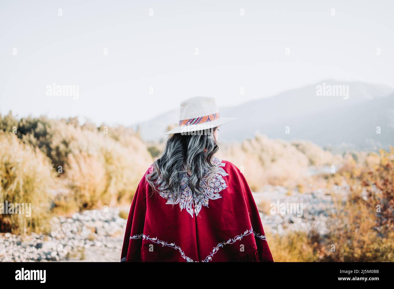 Traditional latin american woman wearing a red poncho and a hat seen ...
